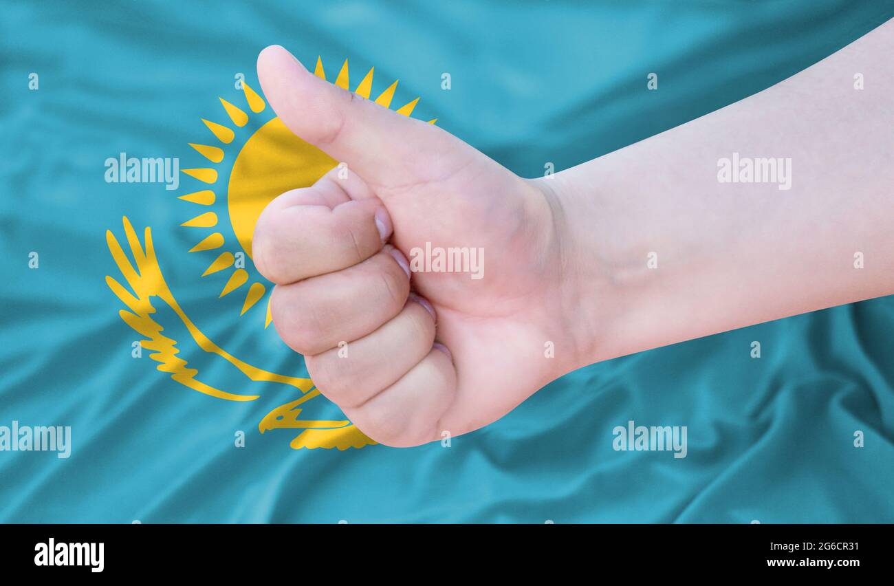 Hand makes a thumbs up sign on the background of the flag of Kazakhstan ...