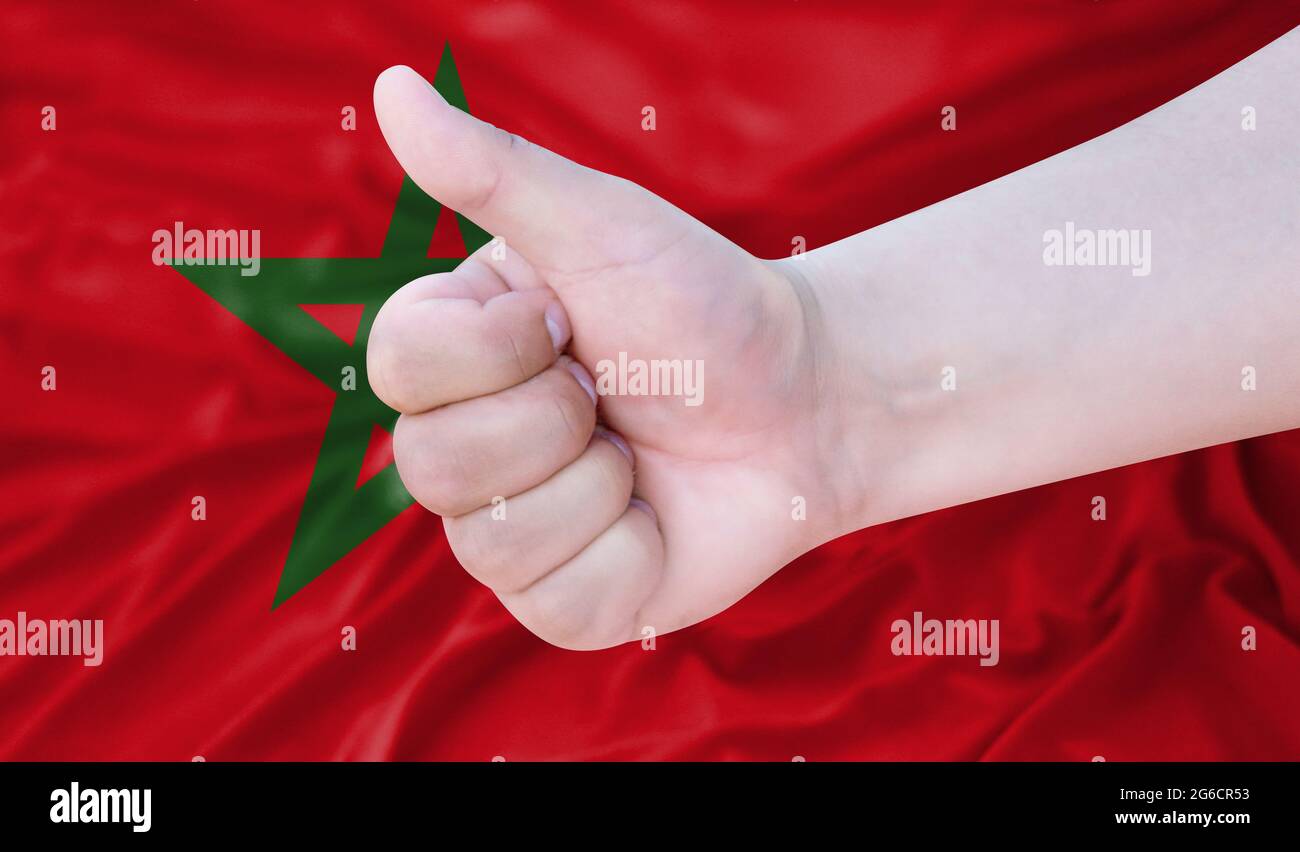 Hand makes a thumbs up sign on the background of the flag of Morocco ...