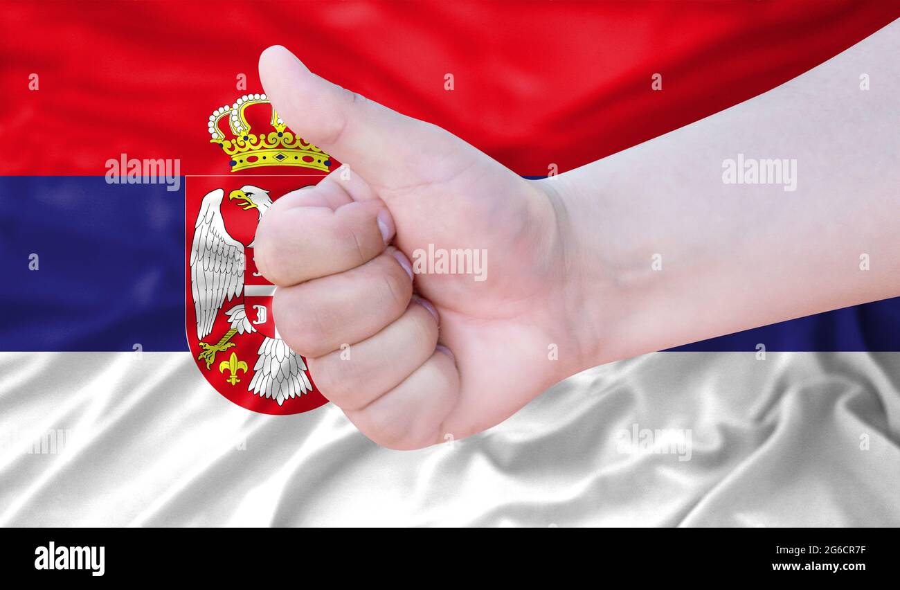 Hand makes a thumbs up sign on the background of the flag of Serbia ...