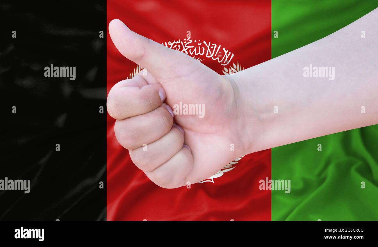 Hand makes a thumbs up sign on the background of the flag of ...