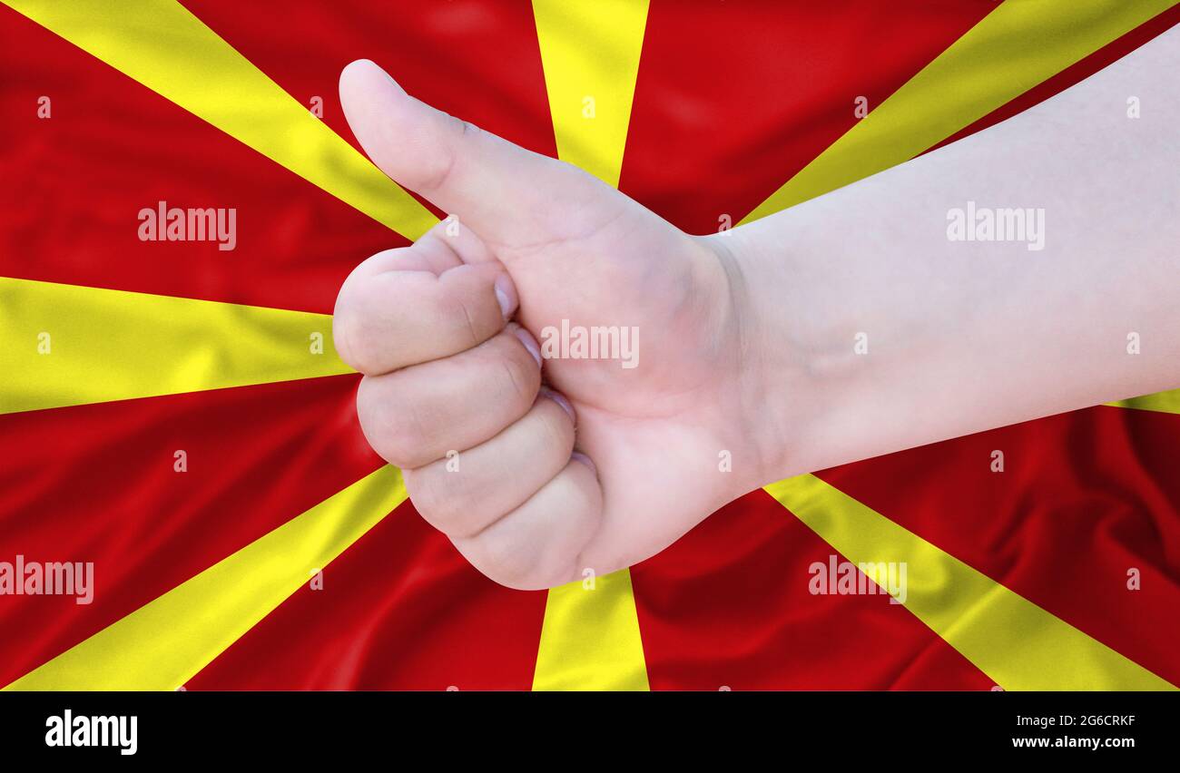 Hand makes a thumbs up sign on the background of the flag of Macedonia ...