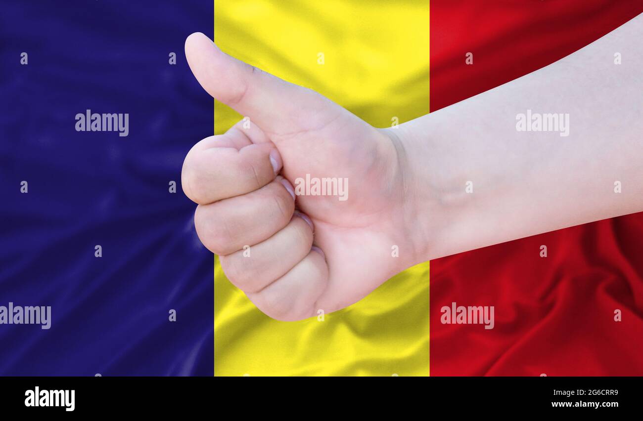 Hand makes a thumbs up sign on the background of the flag of Romania ...