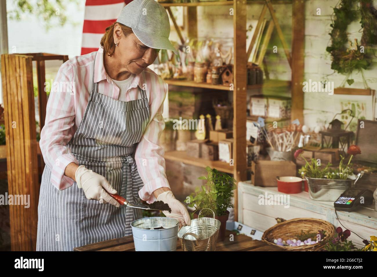 Professional female florist planting seedling in shop Stock Photo - Alamy