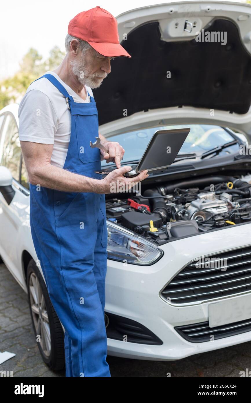Car mechanic using laptop for checking car engine Stock Photo - Alamy