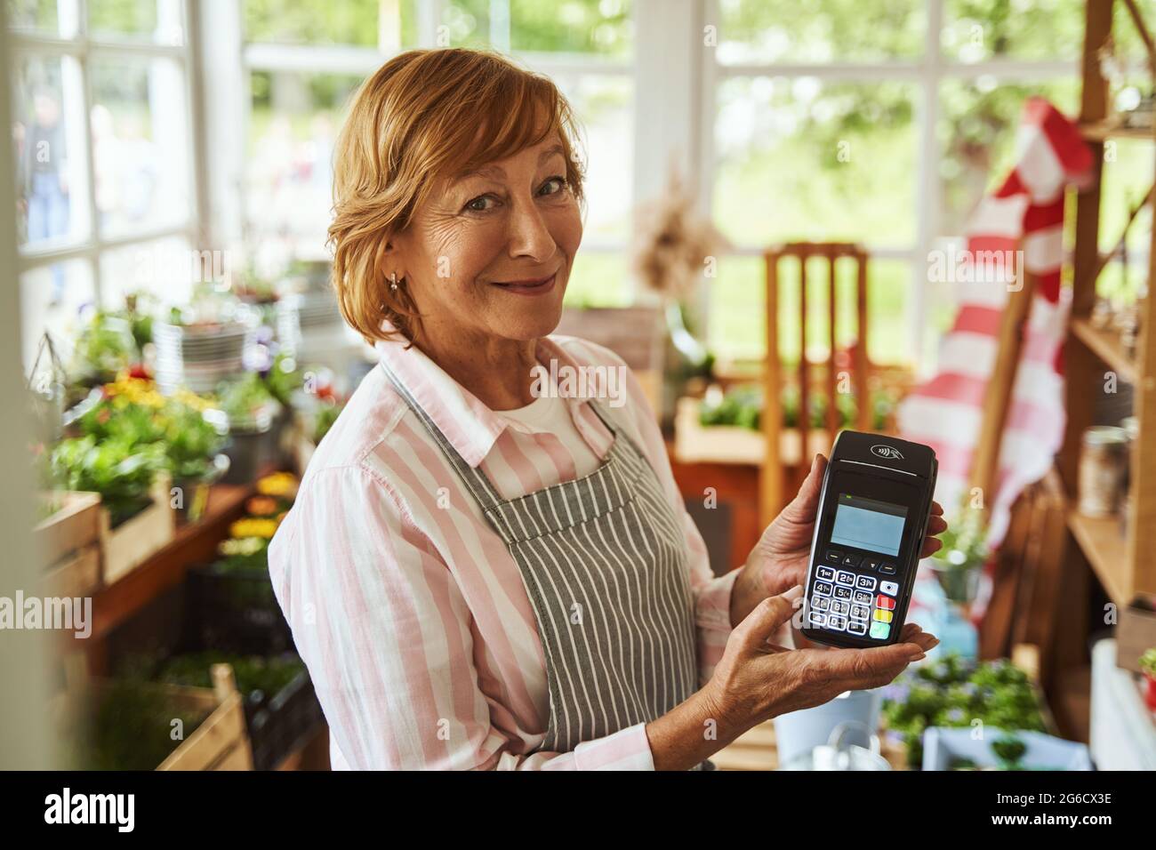 Cheerful female showing pos terminal in her rural shop Stock Photo - Alamy