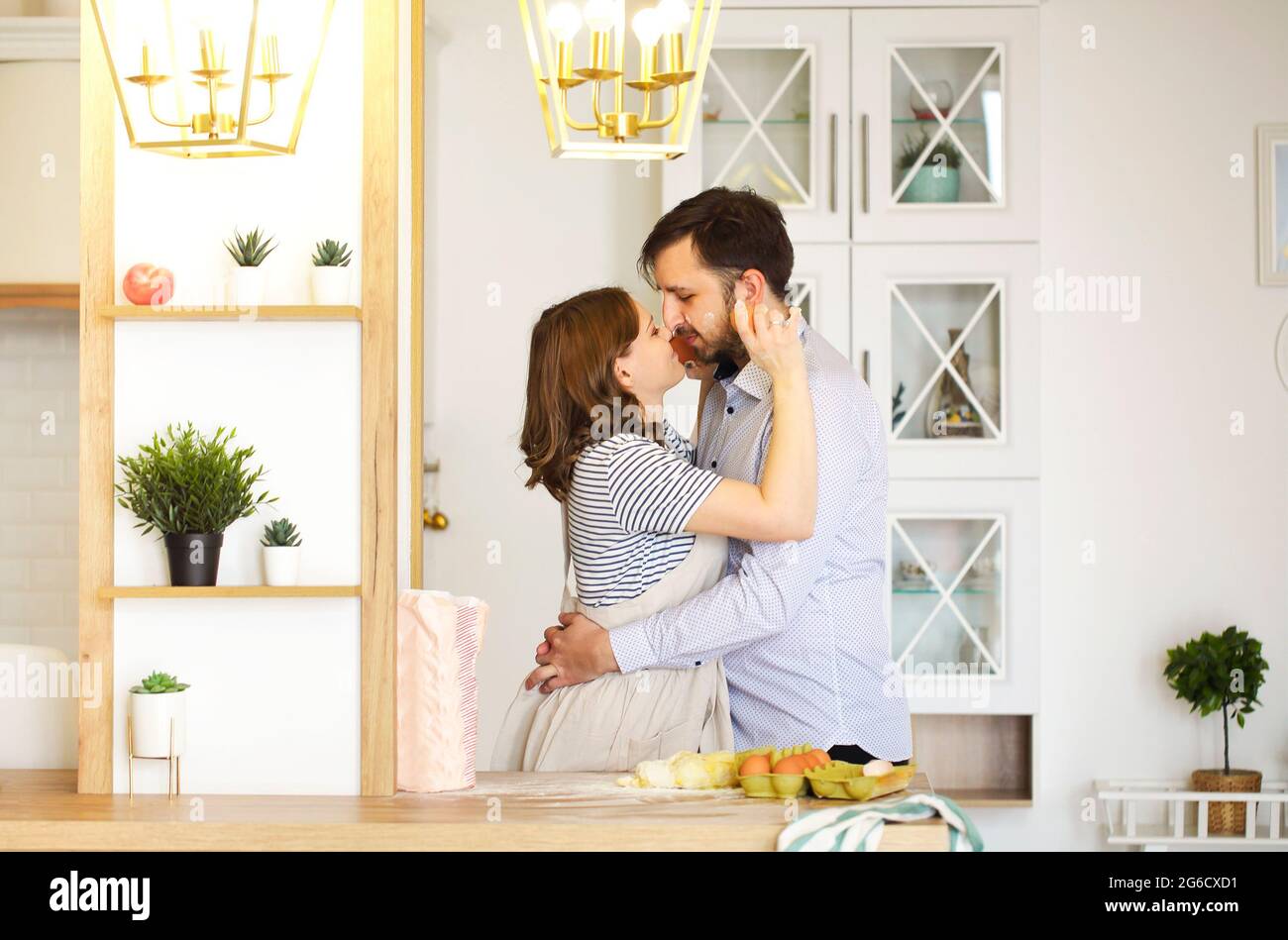 Side view of delighted couple in love hugging in kitchen while cooking ...