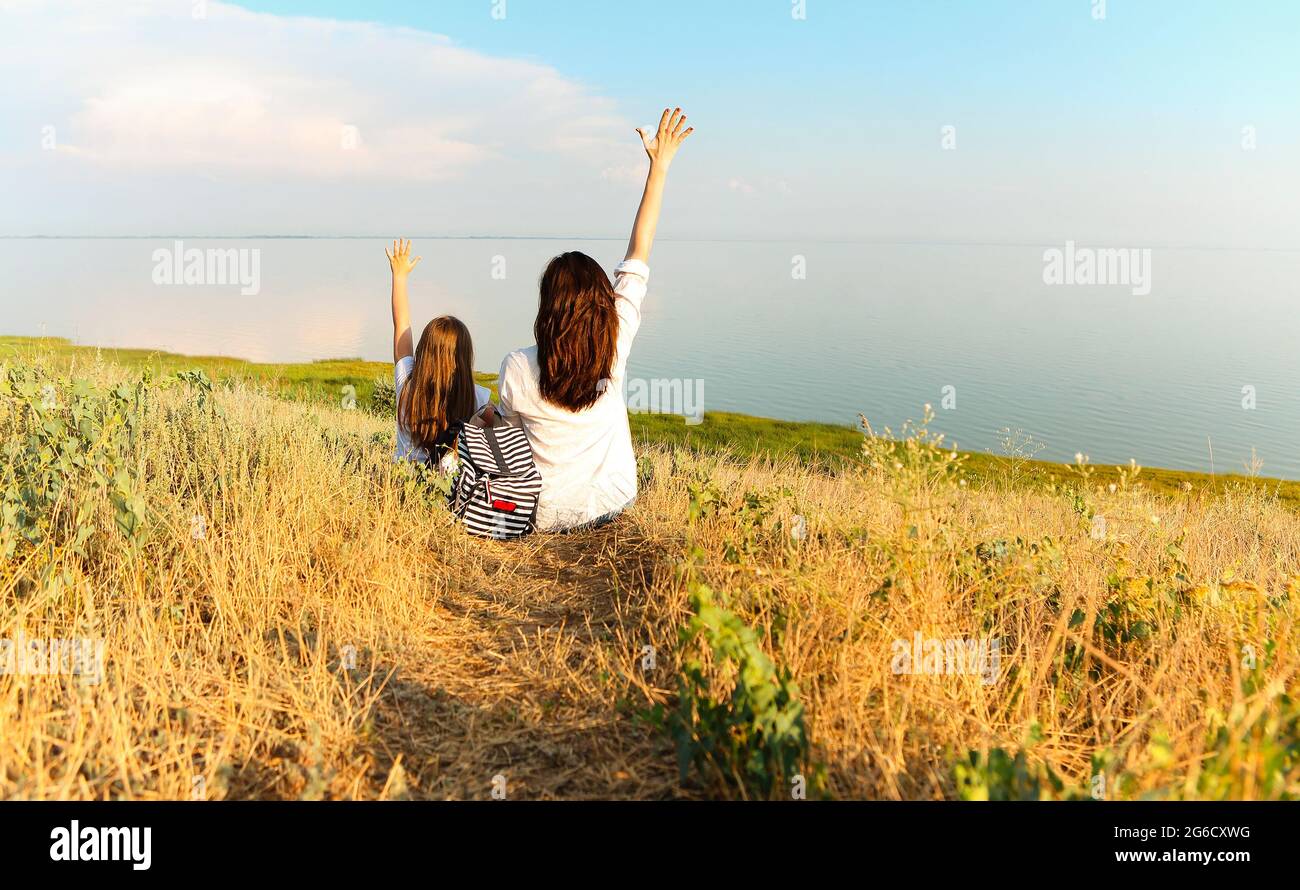 Back view of unrecognizable woman hugging girl while sitting on dried ...