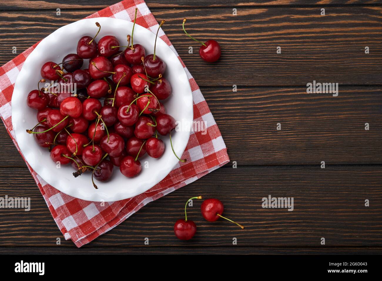 Cherry with water drops on white bowl on dark brown stone table. Fresh ...