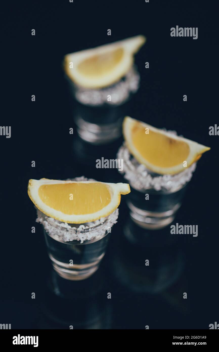 Tequila shots with salt and lemon placed on reflective surface against ...