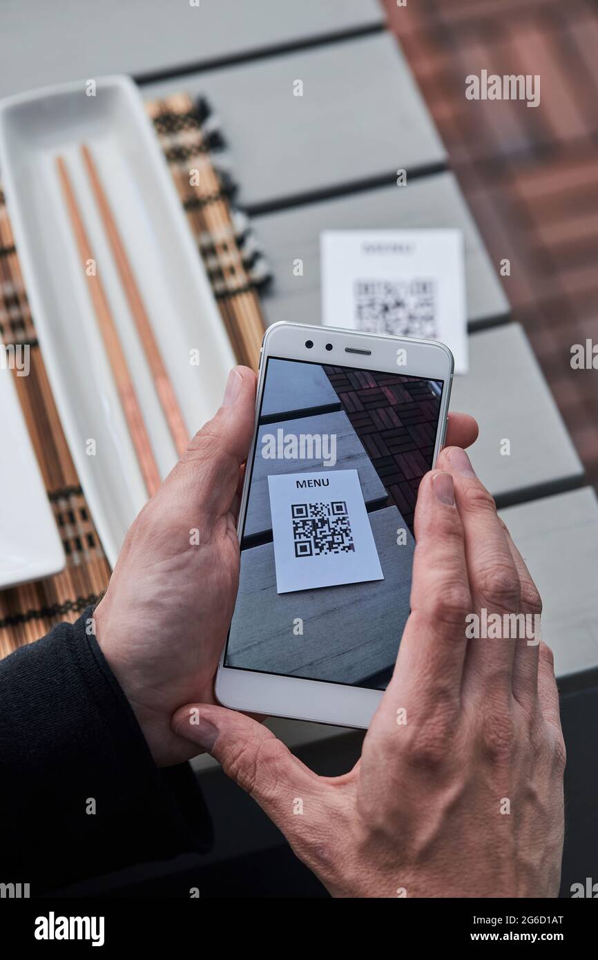 From above of crop unrecognizable male using smartphone and scanning QR ...