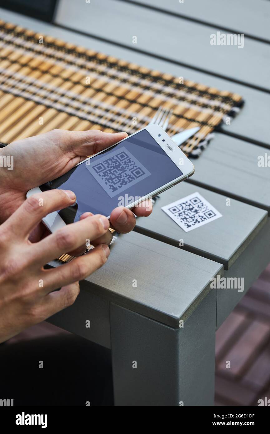 From above of crop unrecognizable male using smartphone and scanning QR ...