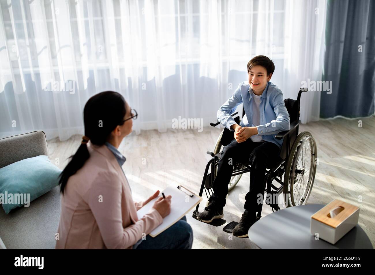 Successful psychotherapy. Happy impaired teen boy in wheelchair sharing ...