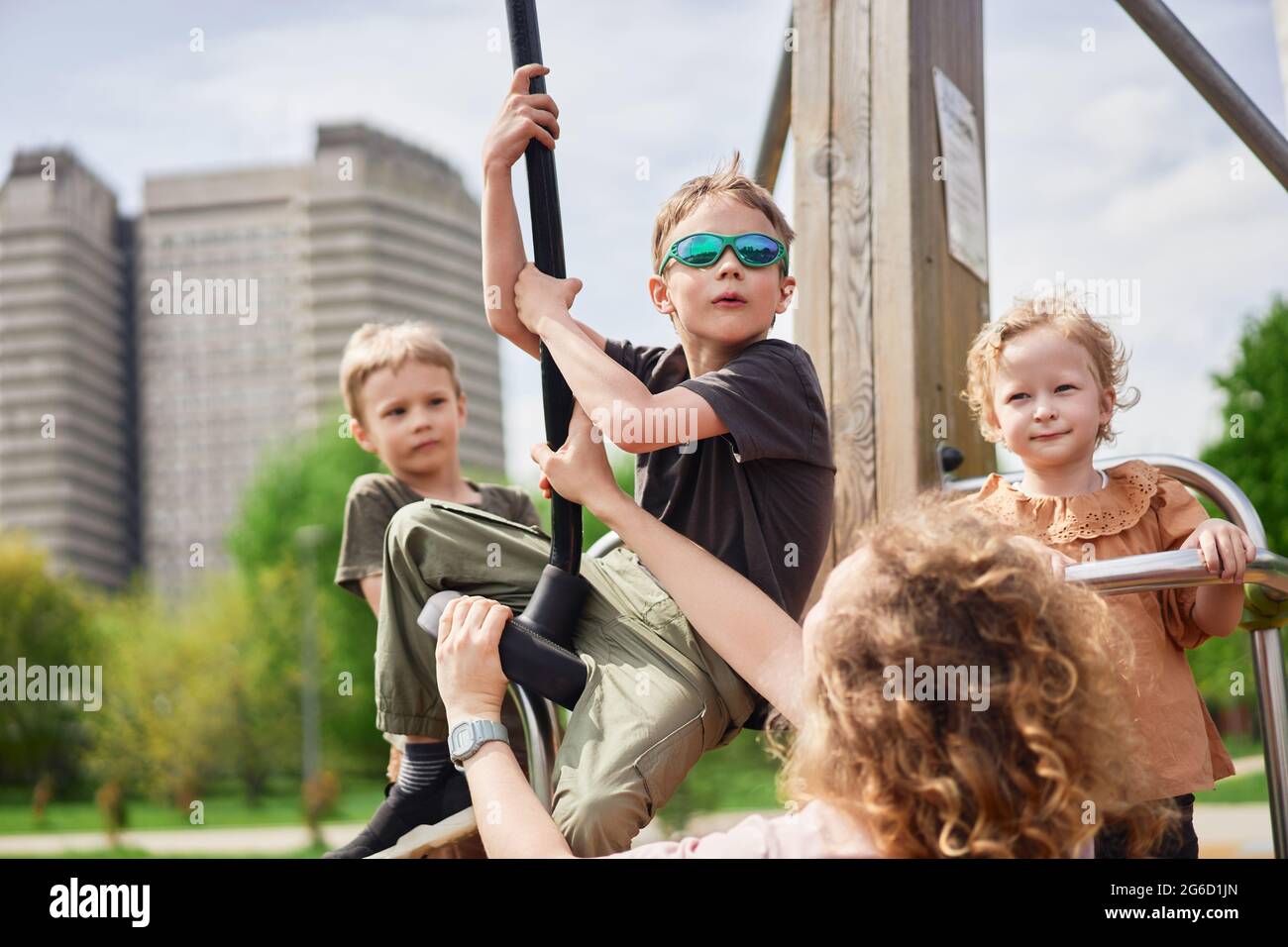 Company of cute kids playing together on playground in city while ...