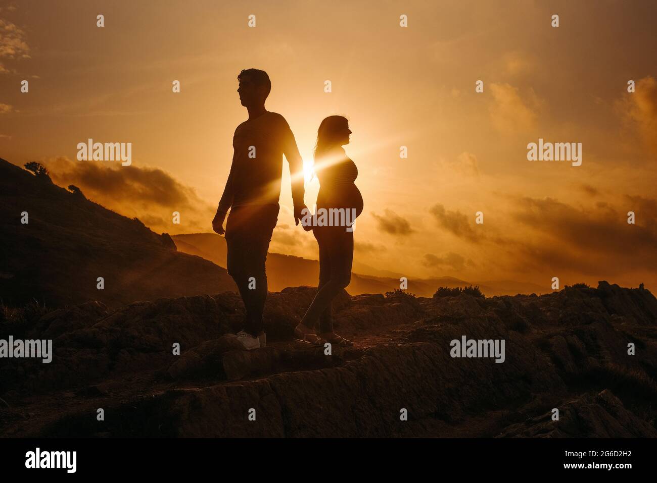 Low angle side view silhouettes of unrecognizable couple expecting baby ...