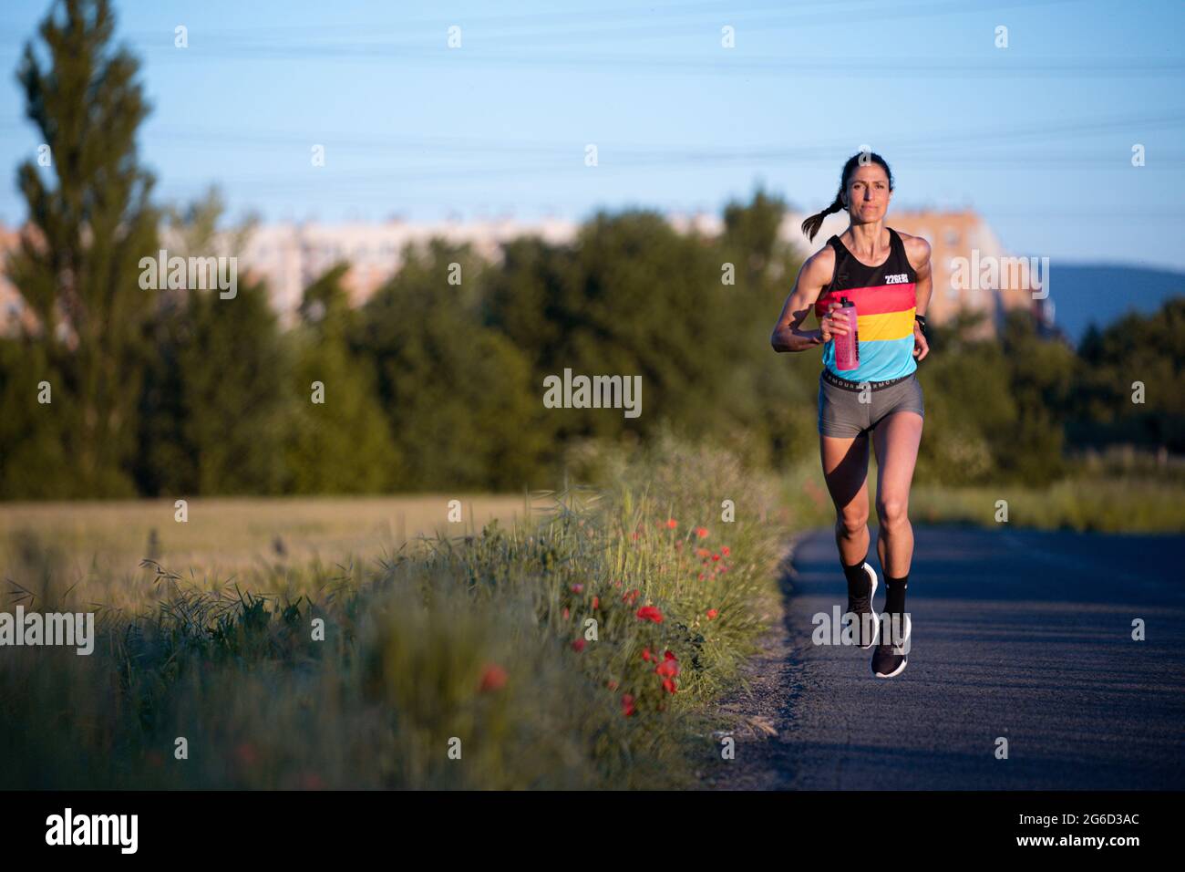 Athlete girl running on a road in the middle of nature Stock Photo - Alamy