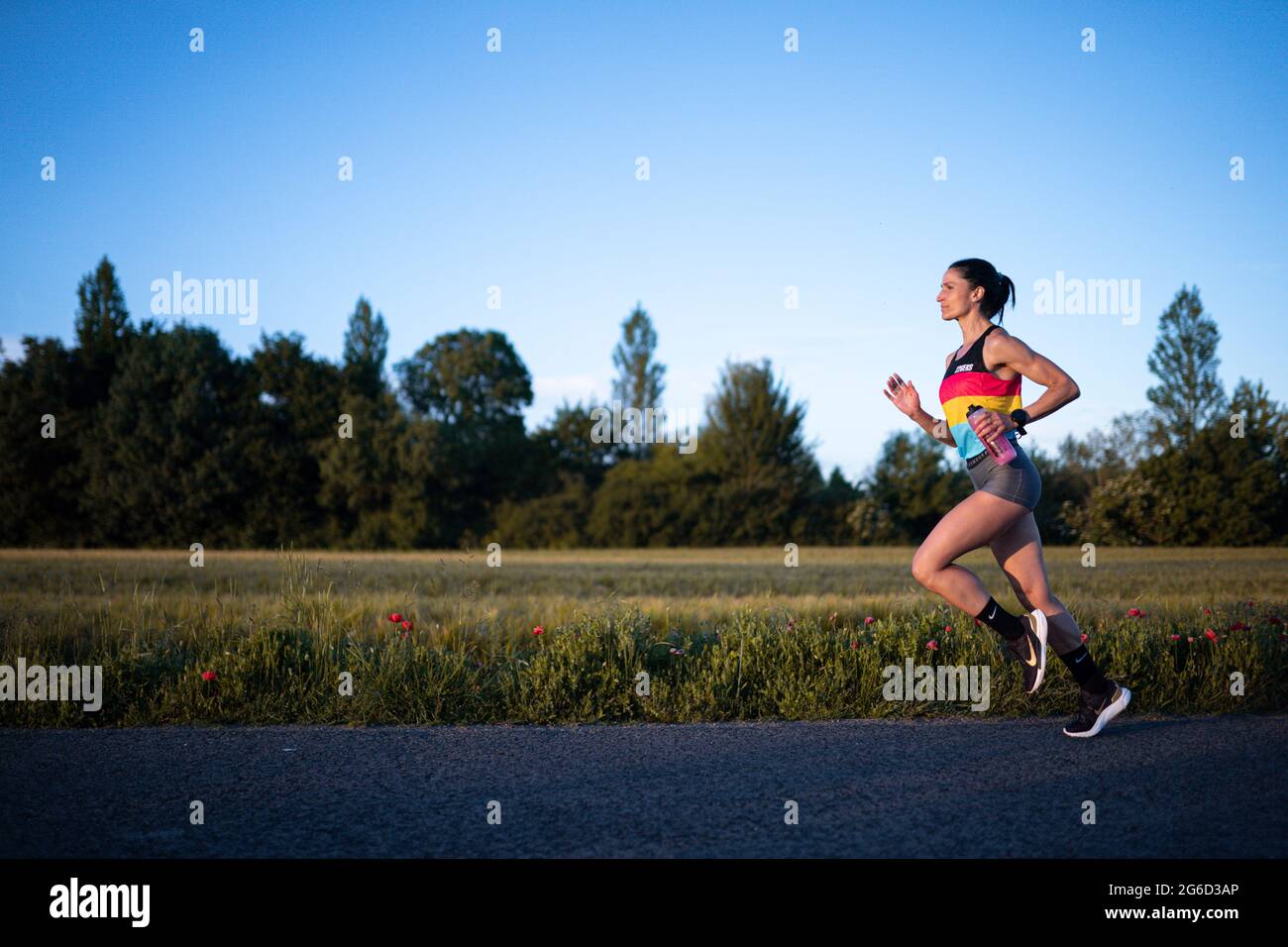 Athlete girl running on a road in the middle of nature Stock Photo - Alamy