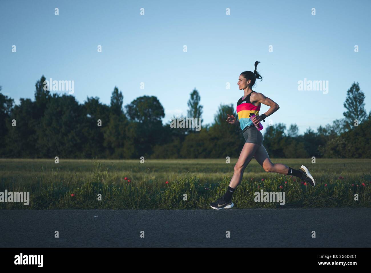 Athlete girl running on a road in the middle of nature Stock Photo - Alamy