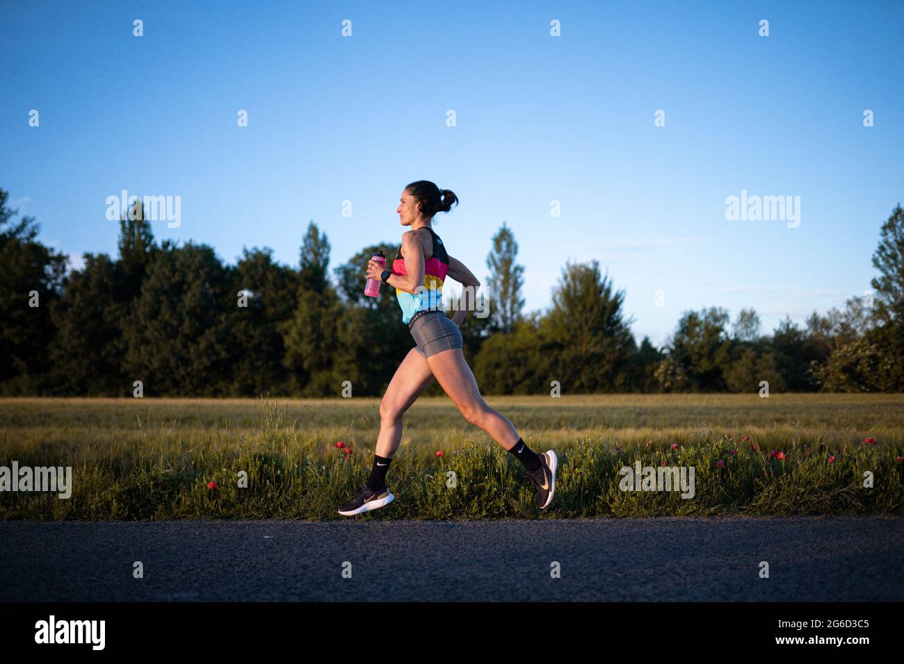 Athlete girl running on a road in the middle of nature Stock Photo - Alamy