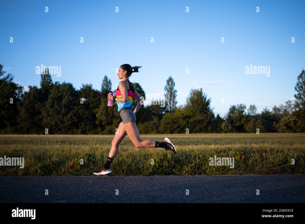 Athlete girl running on a road in the middle of nature Stock Photo - Alamy
