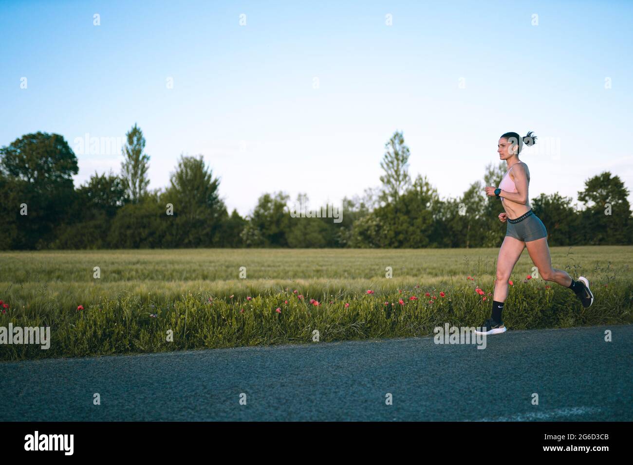 Athlete girl running on a road in the middle of nature Stock Photo - Alamy