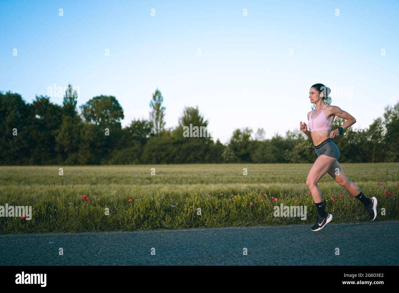 Athlete girl running on a road in the middle of nature Stock Photo - Alamy