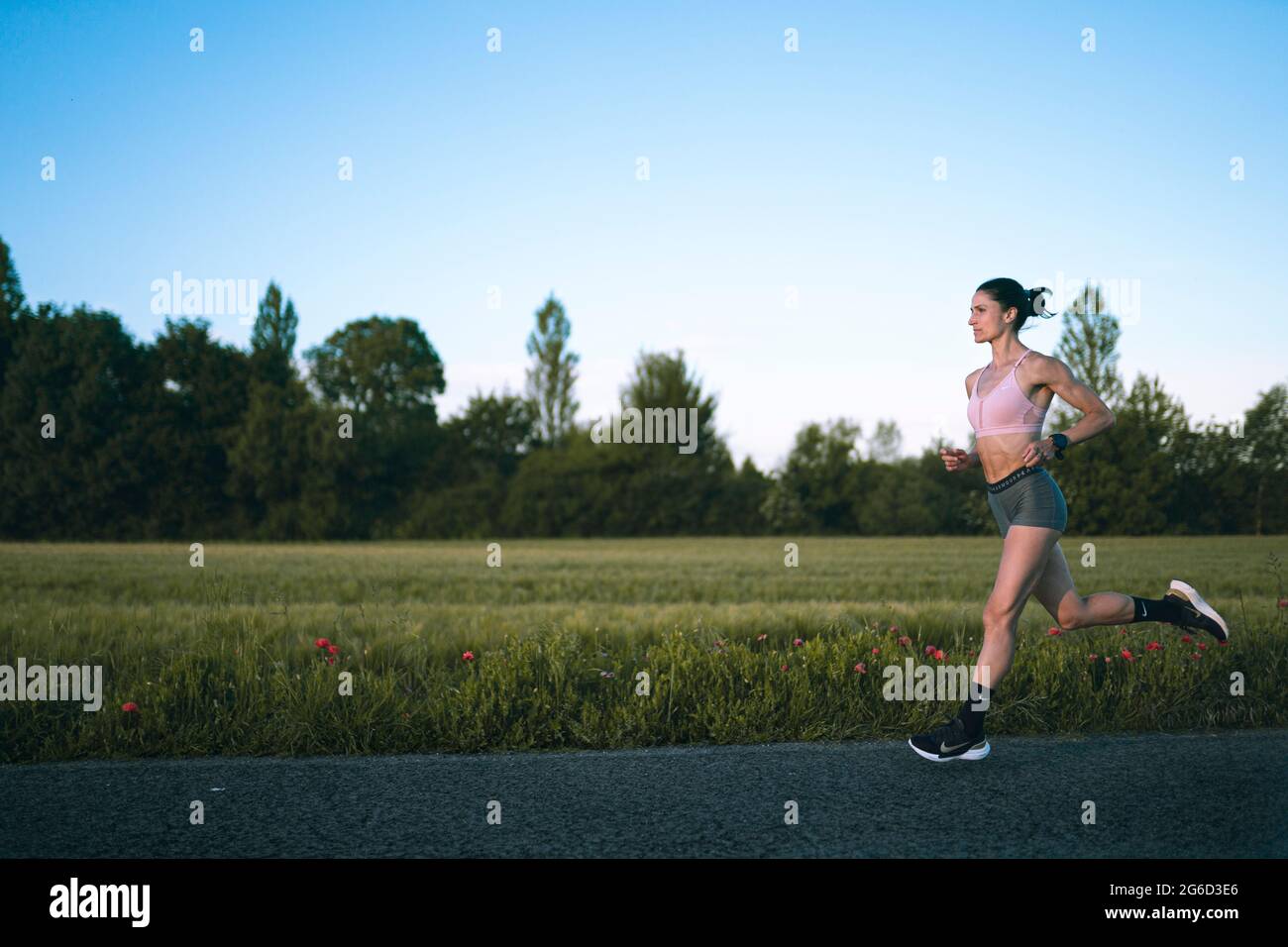 Athlete girl running on a road in the middle of nature Stock Photo - Alamy