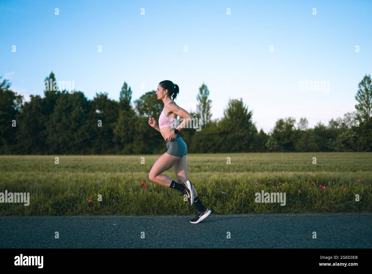 Athlete girl running on a road in the middle of nature Stock Photo - Alamy