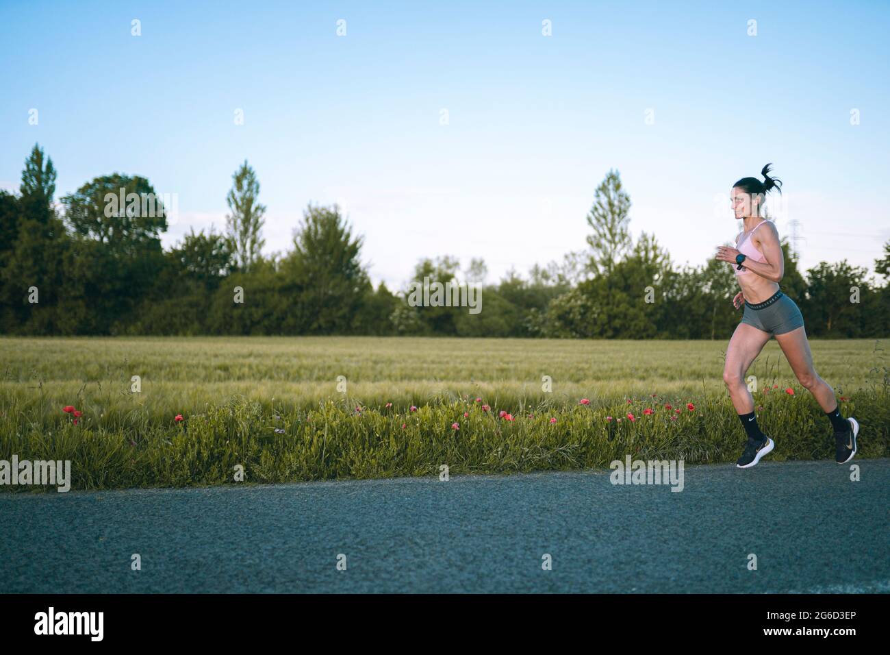 Athlete girl running on a road in the middle of nature Stock Photo - Alamy