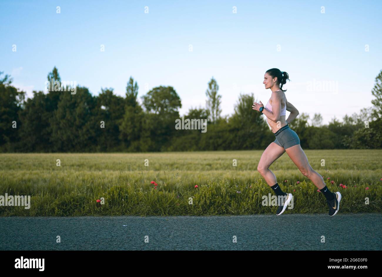 Athlete girl running on a road in the middle of nature Stock Photo - Alamy