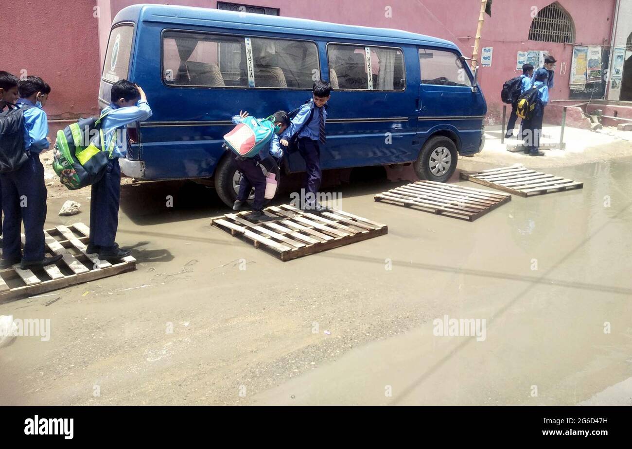 School students pass through stagnant sewerage water at a street in ...