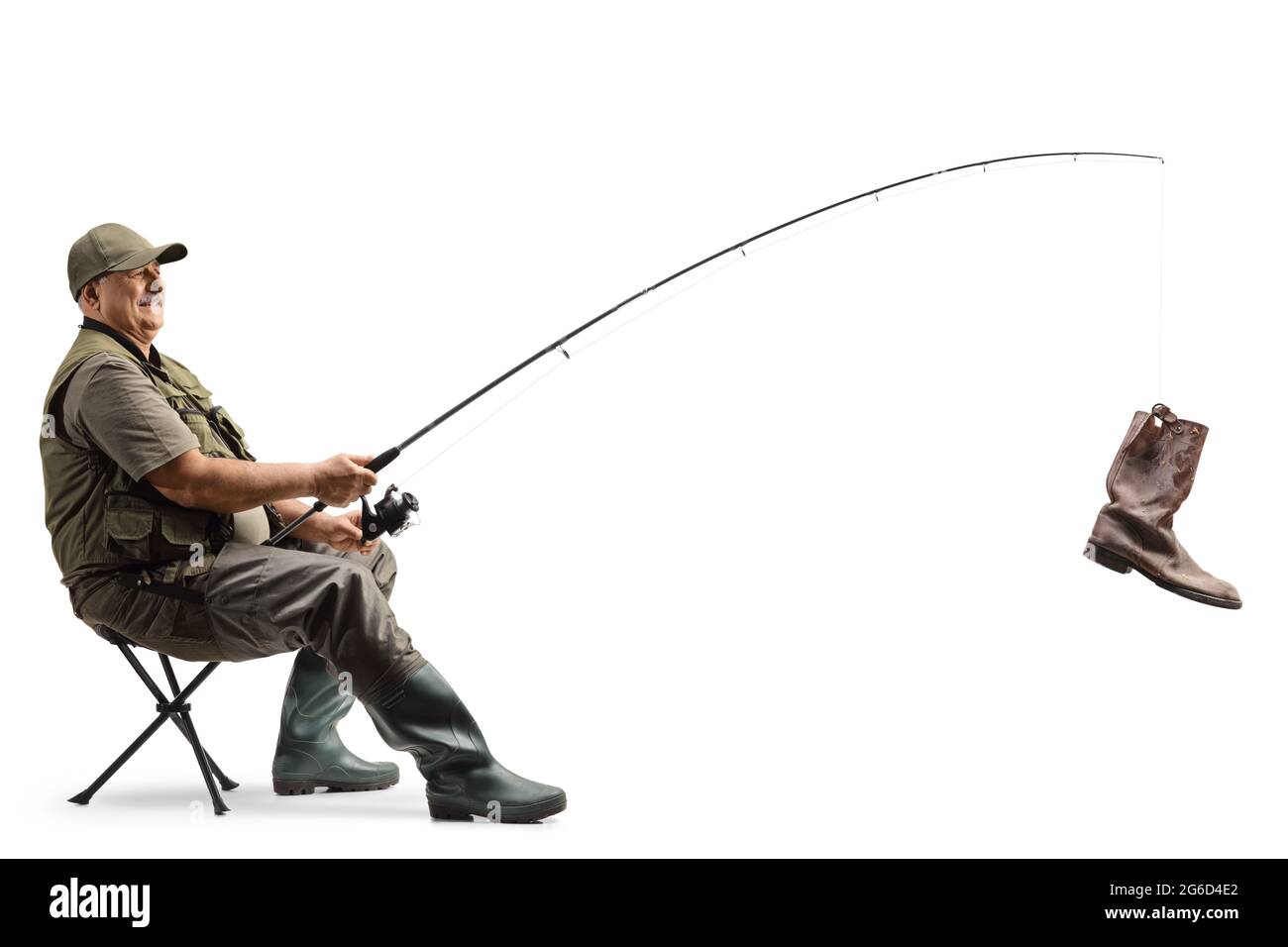 Mature fisherman sitting on a chair with a fishing rod and an old boot ...