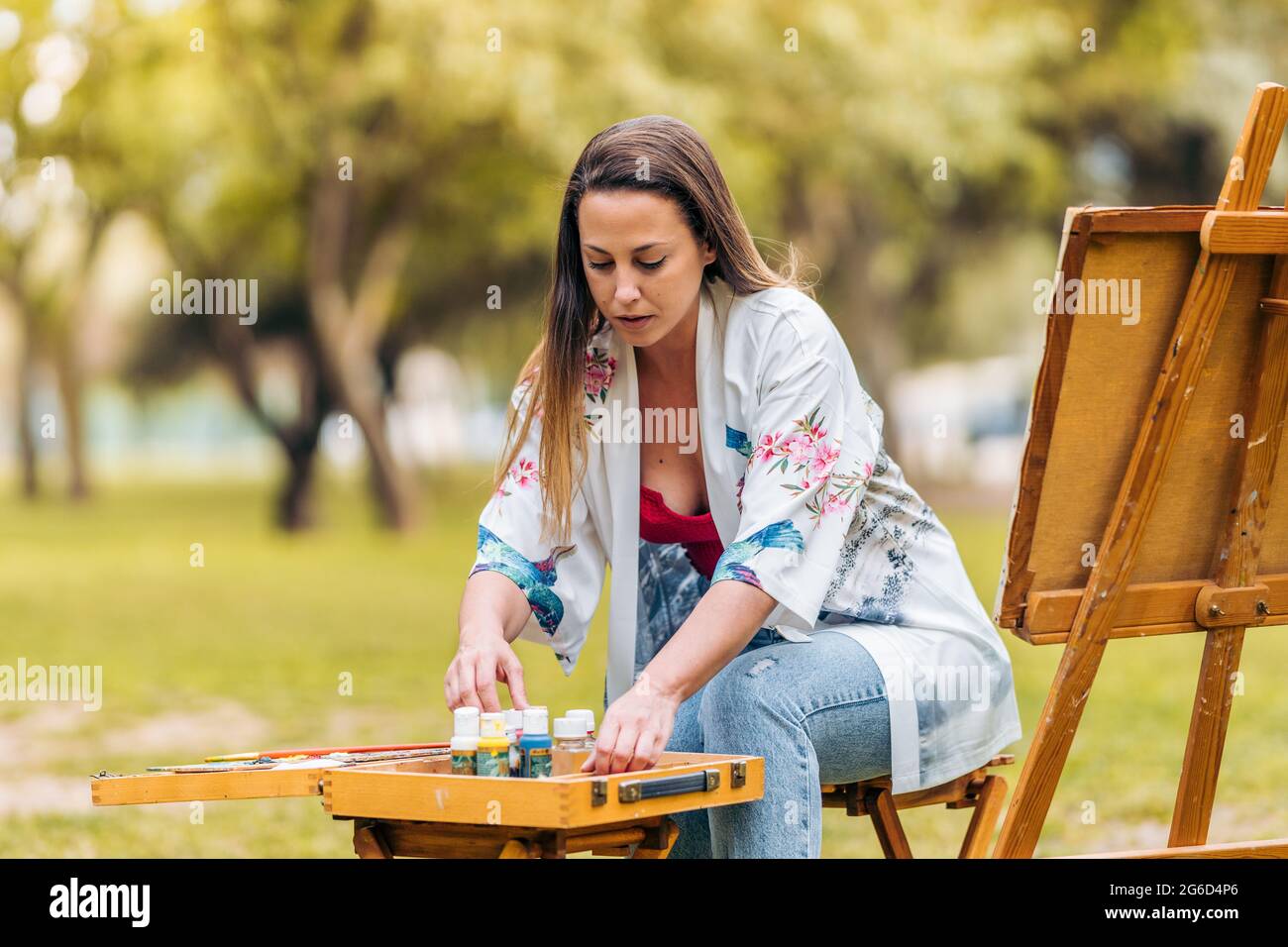 Artist arranging pots of paint on a table while sitting in front of a ...