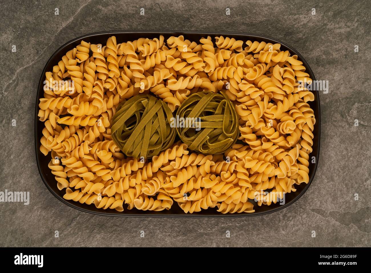 Top view of tray filled with raw fusilli and tagliatelle pasta and ...