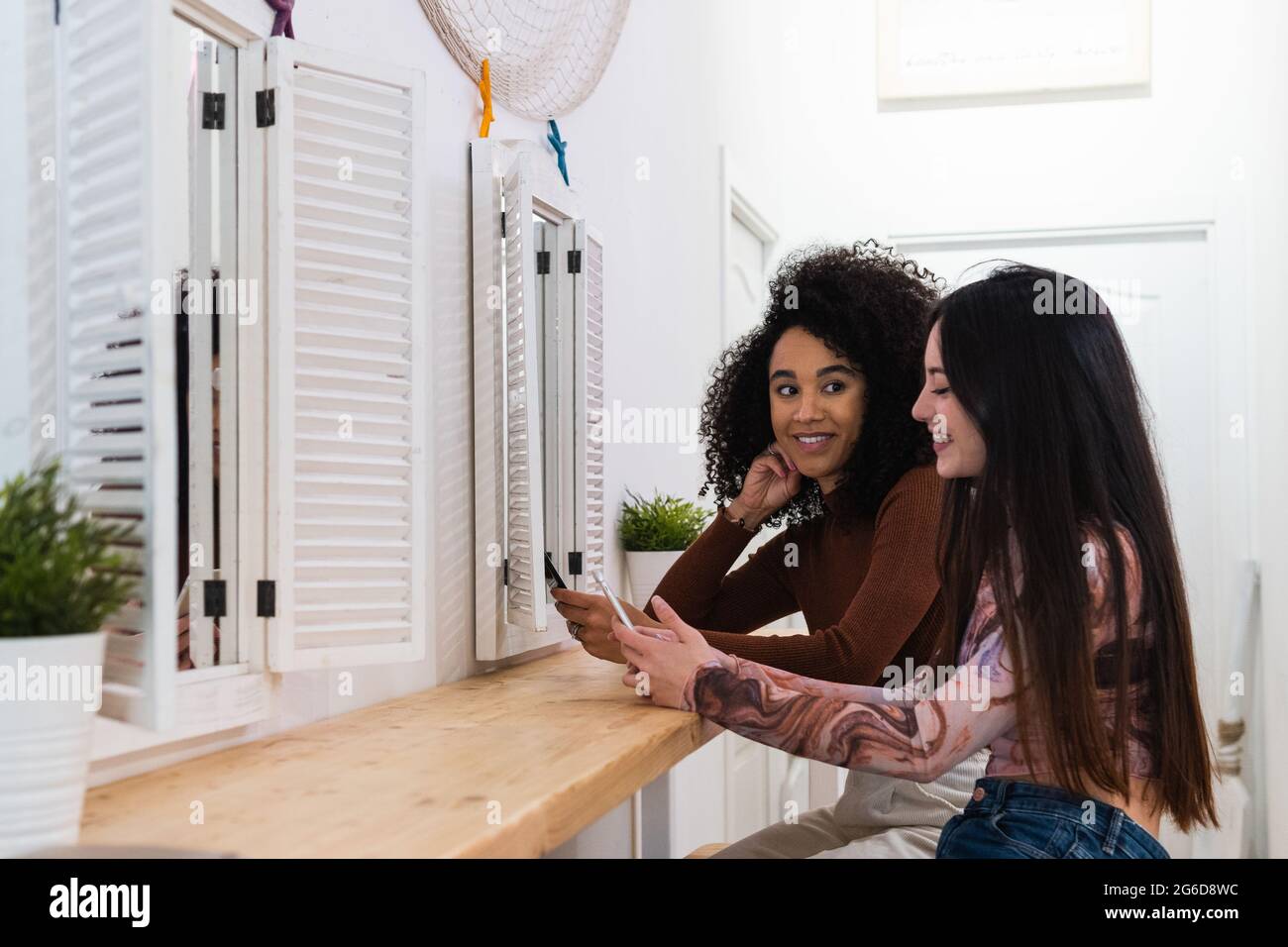 Side view of content diverse female friends sitting at counter in bar ...