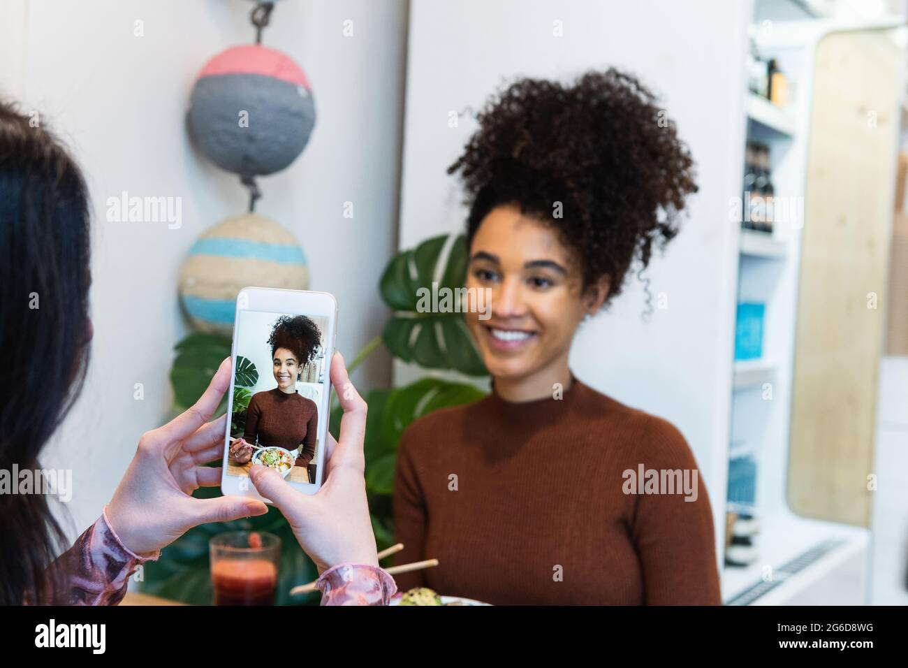Crop unrecognizable female taking photo of African American friend ...