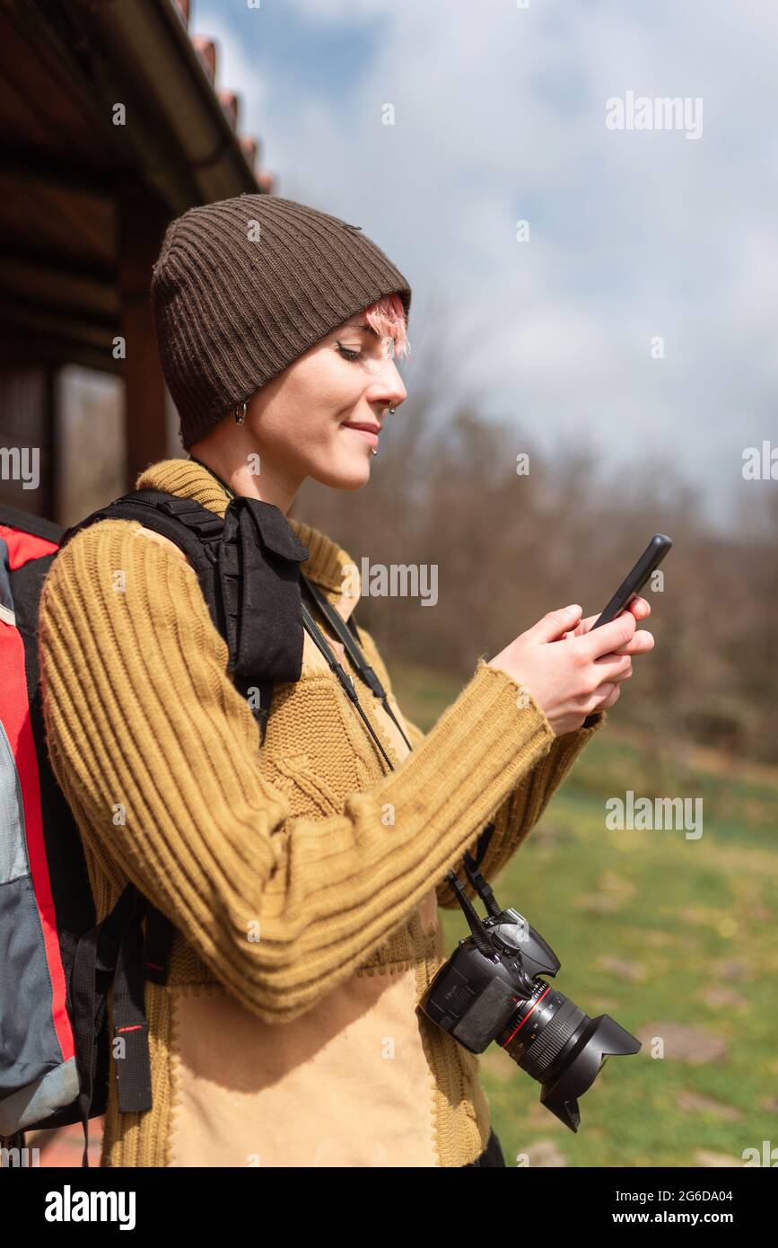 Side view of cheerful female explorer with backpack standing in nature ...