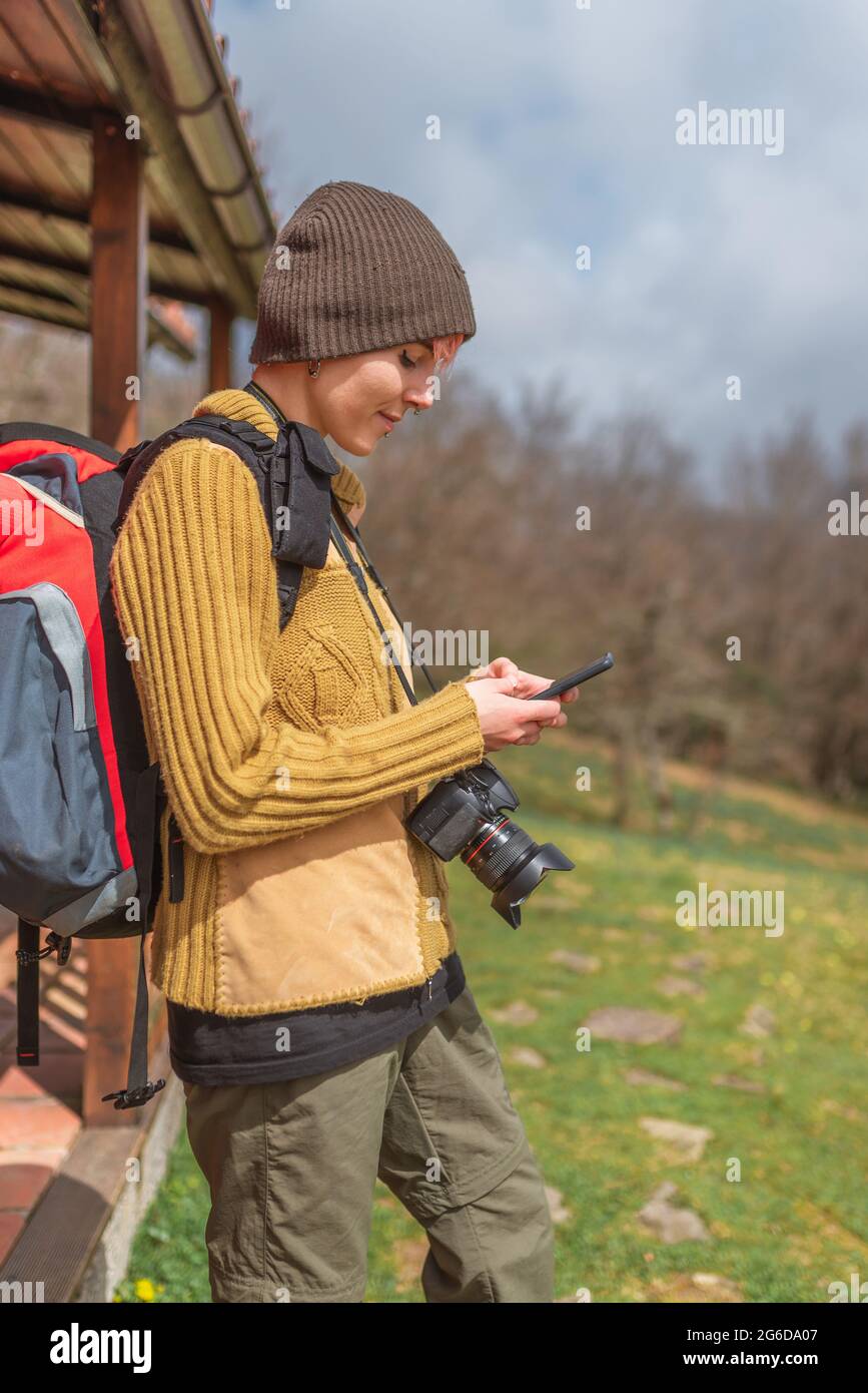 Side view of cheerful female explorer with backpack standing in nature ...