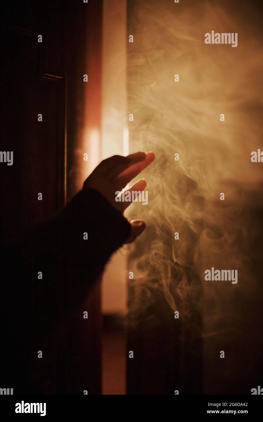 Raised hand of crop faceless person in dark studio with smoke ...