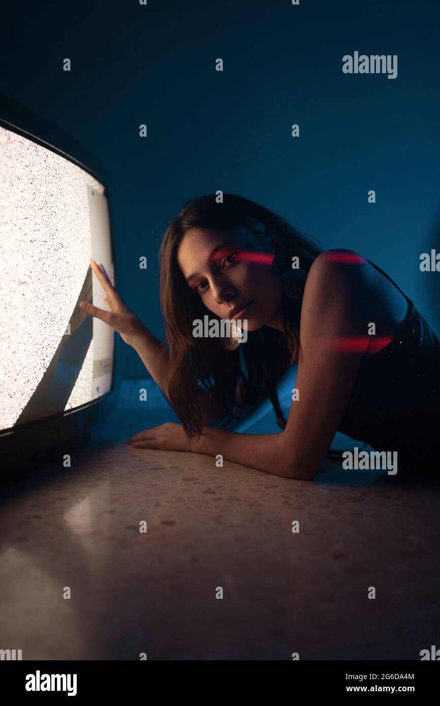 Side view of female model in black dress lying down on floor looking at ...