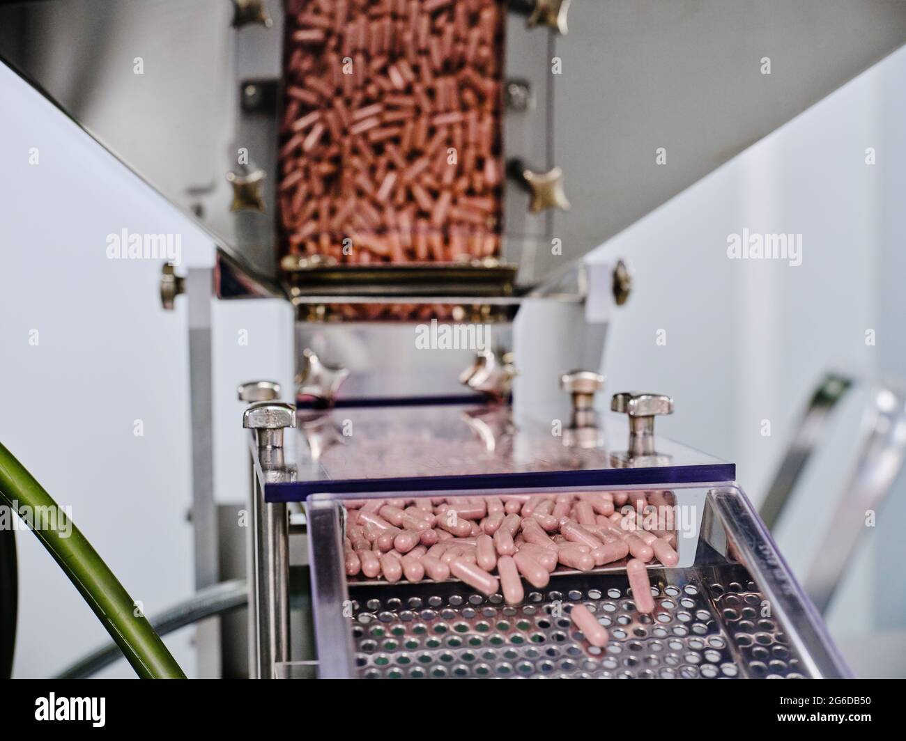 Contemporary pharmaceutical machine with piles of pink pills on ...