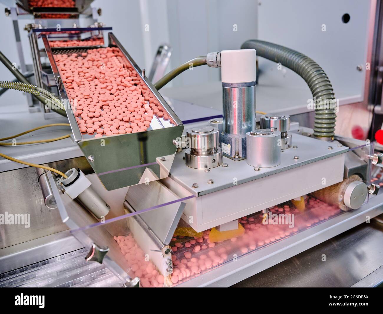 Contemporary pharmaceutical machine with piles of pink pills on ...