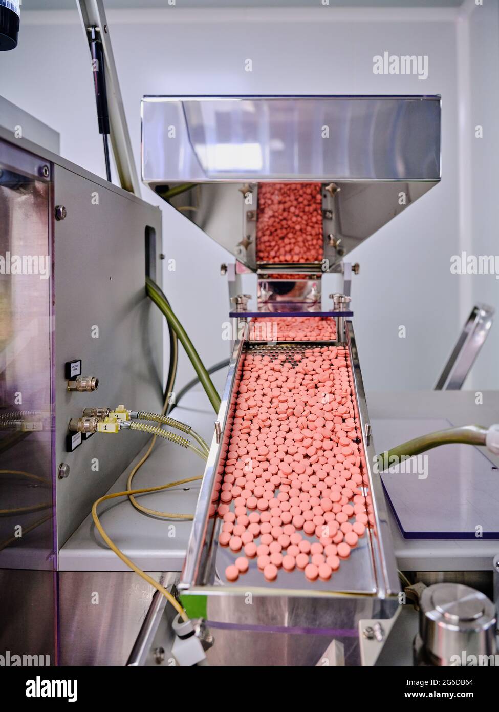Contemporary pharmaceutical machine with piles of pink pills on ...