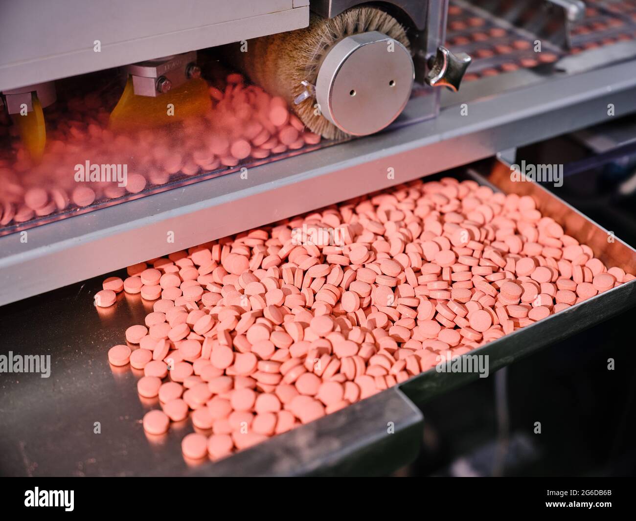 Contemporary pharmaceutical machine with piles of pink pills on ...