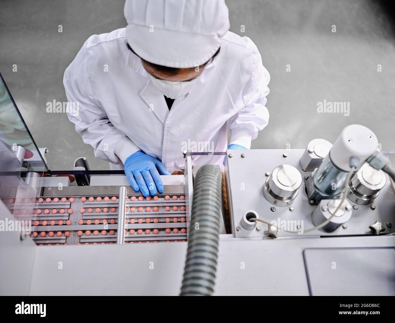 From above female factory worker in uniform operating conveyor with ...