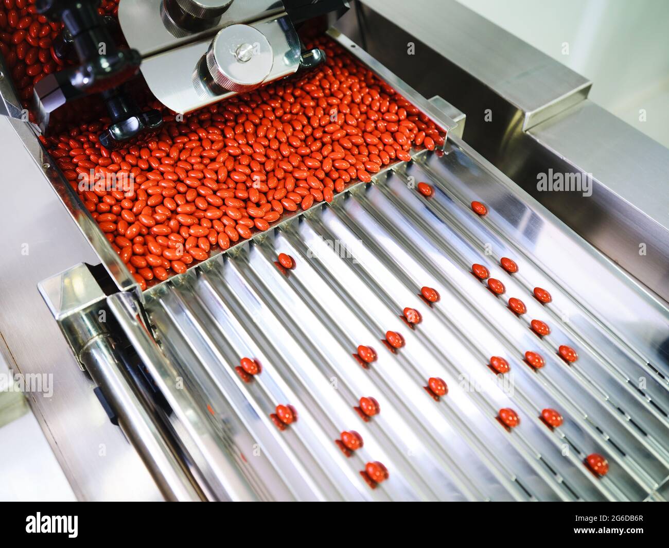 Contemporary pharmaceutical machine with piles of pink pills on ...