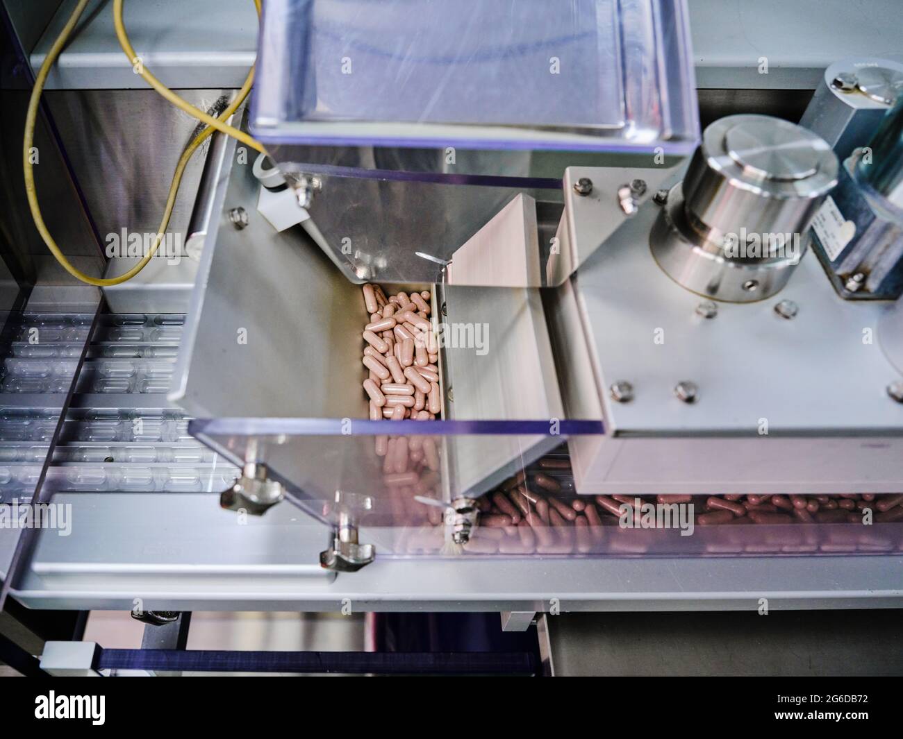 Contemporary pharmaceutical machine with piles of pink pills on ...