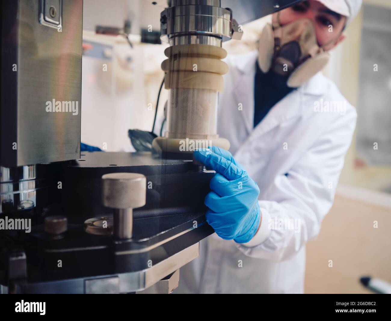 Male worker in protective uniform operating capsule filling machine at ...