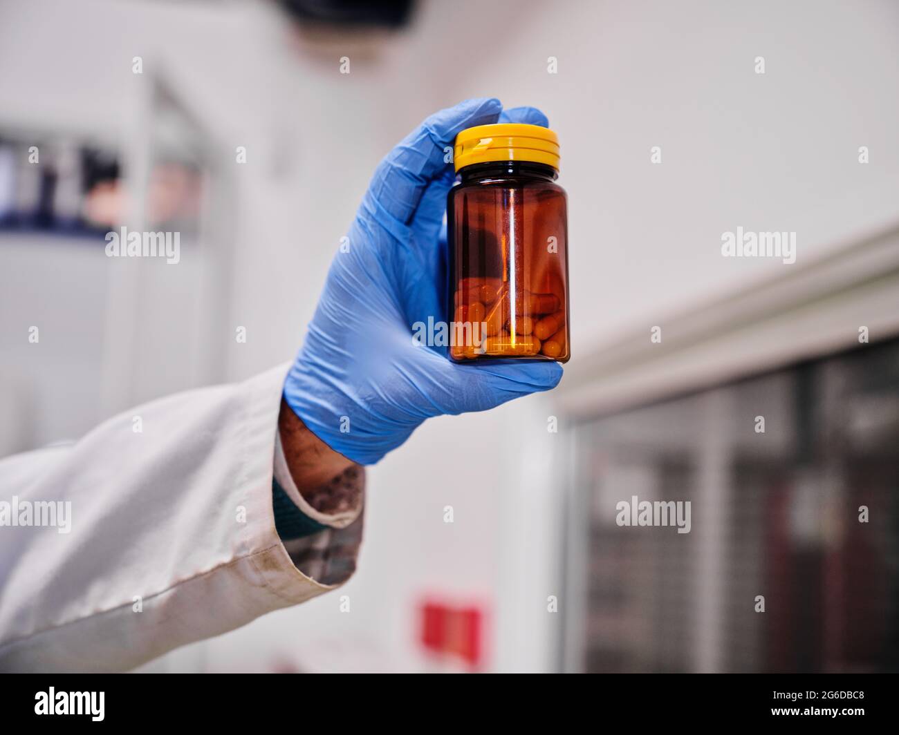 Crop anonymous scientist in protective gloves standing showing pile of ...