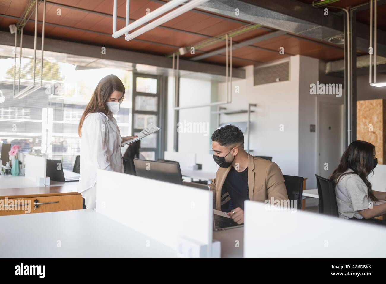 Male and female coworkers in protective masks working on project in ...
