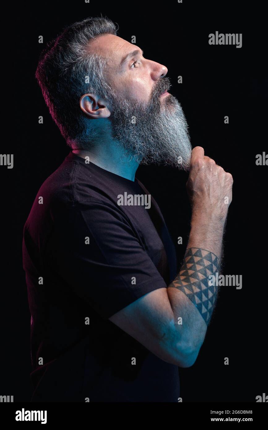 Side view of handsome mature male with gray beard on black background ...